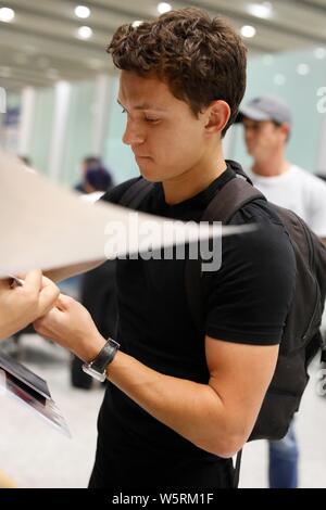 English actor Tom Holland signs autographs for fans as he arrives on ...