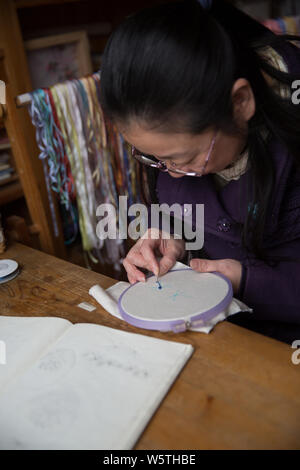 Chinese craftswoman Yuan Weilin makes an embroidery through silk ribbon ...