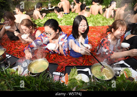 Visitors enjoy hot pots while soaking in a "Yuan Yang" hotpot-style hot ...