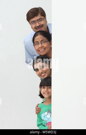 Family hiding behind a placard Stock Photo - Alamy