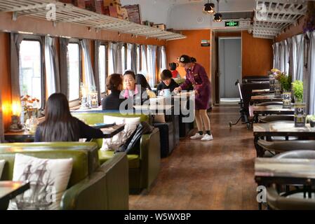 A waitress dressed as a train attendant serves customers at a ...