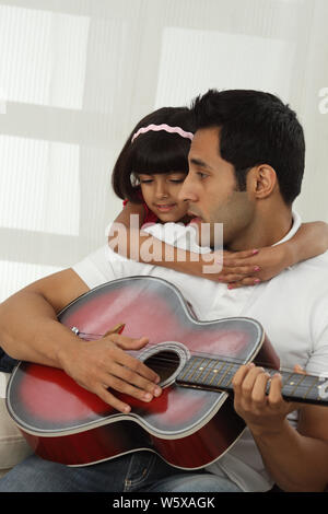 Child hugging man playing guitar Stock Photo - Alamy