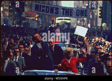 Richard M. Nixon in a campaign motorcade standing on the back of car ...