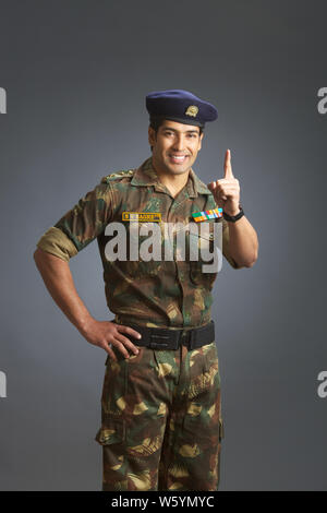 Army soldier pointing upward smiling Stock Photo - Alamy