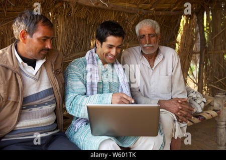Farmer explaining to villager on a laptop Stock Photo - Alamy