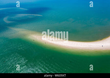 Aerial view of a sand spit leading into the ocean from a green ...