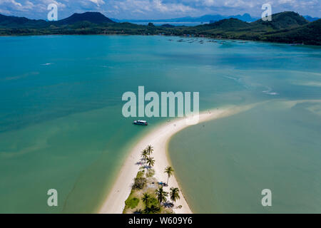 Aerial view of a sand spit leading into the ocean from a green ...