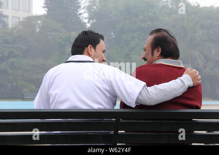 Doctor sitting with patient on bench Stock Photo - Alamy