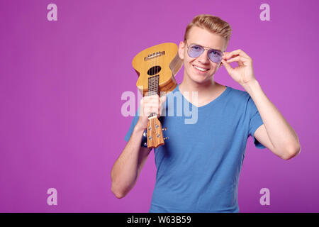 smiling man with ukulele in hands on purple background Stock Photo - Alamy
