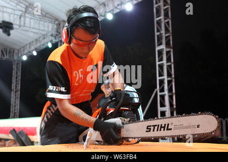 A Chinese contestant changes the saw blade of his chainsaw during the ...