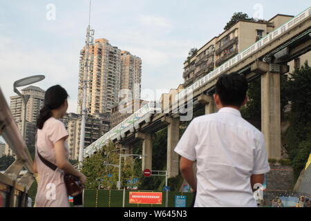 Visitors watch a monorail train of Chongqing Light Rail Line 2 running ...