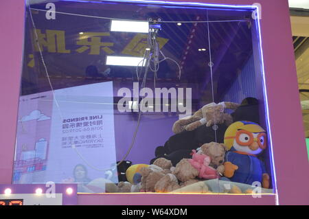 Players grab dolls inside a two-storey human doll-grabbing machine ...