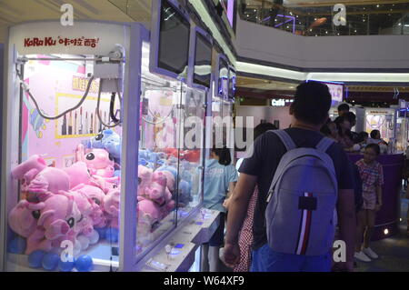 Players grab dolls on ordinary doll-grabbing machines at a shopping ...