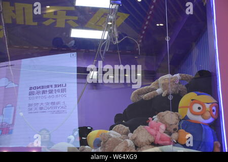 Players grab dolls inside a two-storey human doll-grabbing machine ...