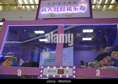 Players grab dolls inside a two-storey human doll-grabbing machine ...