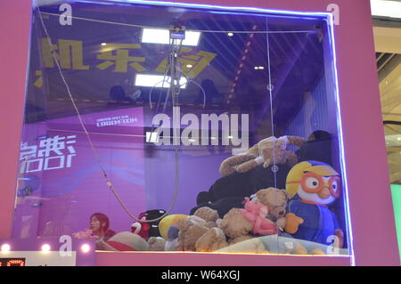 Players grab dolls inside a two-storey human doll-grabbing machine ...