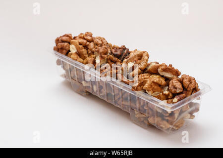 Plastic container with peeled walnuts on the white background. Useful ...