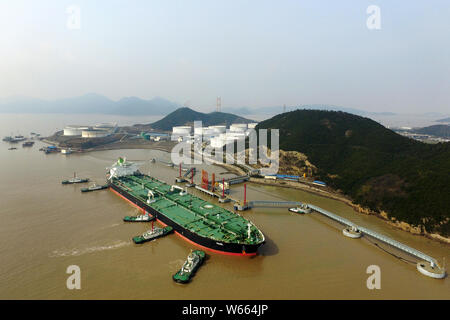 An oil tanker carrying imported crude oil docks at a berth in Qingdao ...