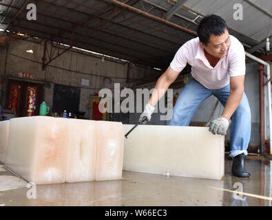 A Chinese worker processes ice blocks in an ice factory in Chaohu city ...