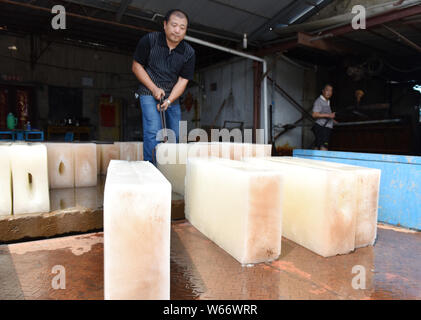 A Chinese worker processes ice blocks in an ice factory in Chaohu city ...