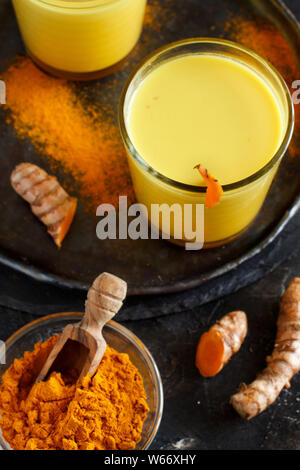 Vibrant orange turmeric powder in white ceramic bowl, garlic, red chili ...