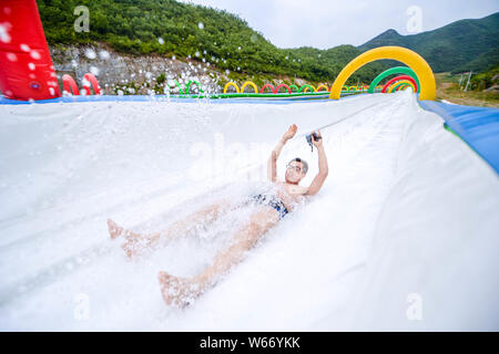 A tourist plays on Asia's longest water slide at Jingzhihu Resort in ...