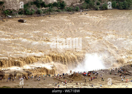 Tourists visit the roaring Hukou Waterfall on the Yellow River after ...