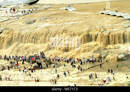 Tourists visit the roaring Hukou Waterfall on the Yellow River after ...