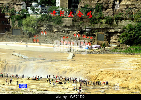 Tourists visit the roaring Hukou Waterfall on the Yellow River after ...