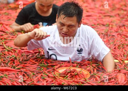 A participant sitting in a big pool filled with chili takes part in an ...
