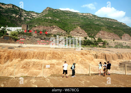 Tourists visit the roaring Hukou Waterfall on the Yellow River after ...