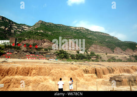 Tourists visit the roaring Hukou Waterfall on the Yellow River after ...