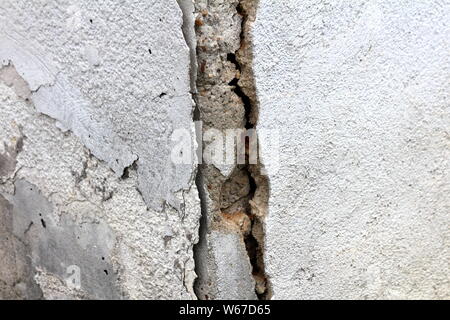 Cracked dilapidated suburban family house wall made of red bricks partially covered with ...
