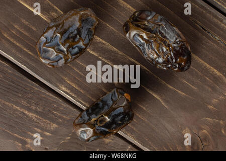 Group of three whole dry brown allspice berries isolated on black glass ...