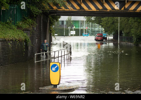 Stockport, UK, 31 Jul 2019. A person wades through the water in the dip ...