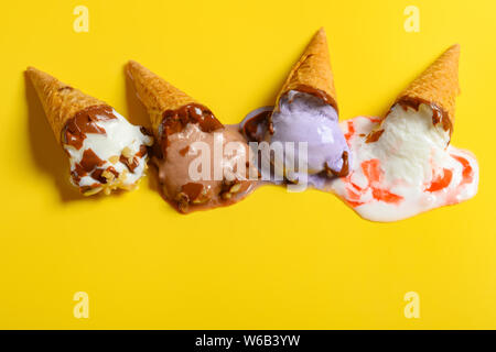 side view multiple flavor ice cream cones melted on yellow background ...