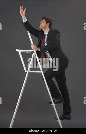 Businessman holding ladder for colleague Stock Photo - Alamy