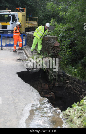 Workers look at a partially collapsed bridge in Poynton, Cheshire ...