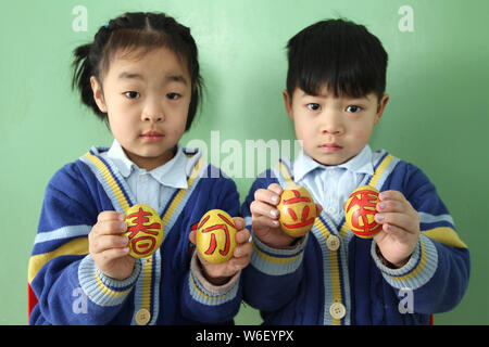 Children show eggs painted with Chinese characters and colors to mark ...