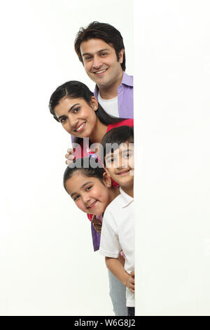 Family hiding behind a blank placard Stock Photo - Alamy