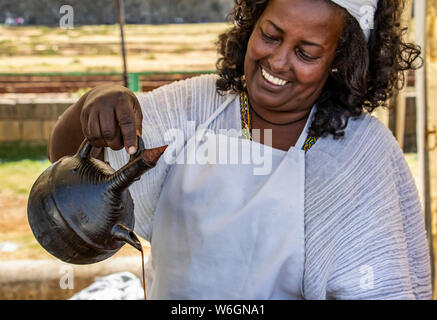 Ethiopian traditional Coffee ceremony women in traditional dress preparing bunna coffee in Addis ...