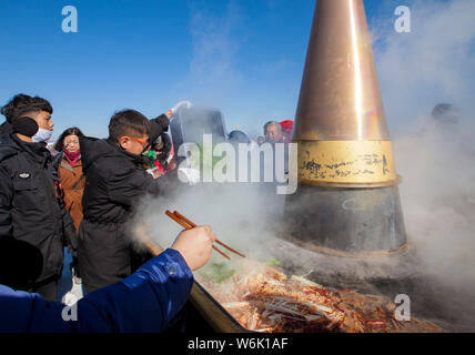 Tourists enjoy a giant hot pot during the first Ice and Snow Hotpot ...