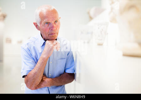 Attentive mature man observing sculptures exhibition in art museum ...