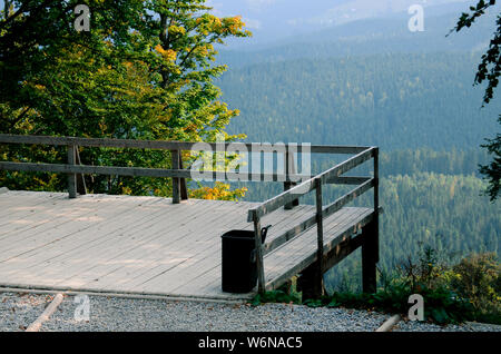 A wooden observation deck over a cliff overlooking the mountain slopes ...