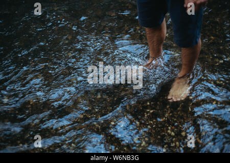 flowing water around the ankles of a human feet standing in a river ...
