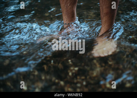 flowing water around the ankles of a human feet standing in a river ...