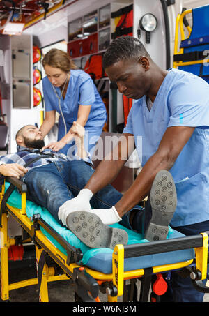 Emergency doctors fixing patient on stretcher in ambulance car Stock ...