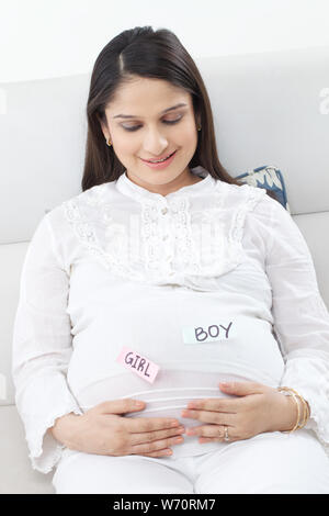 Pregnant woman with sticky note on belly against light blue background ...