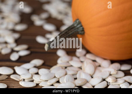 Fresh orange pumpkin and pimpkin seeds close-up on wooden background ...