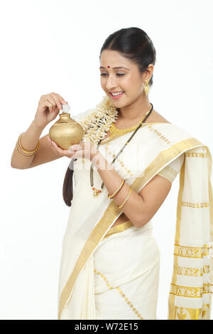 South Indian woman inserting a coin into a piggy bank Stock Photo - Alamy